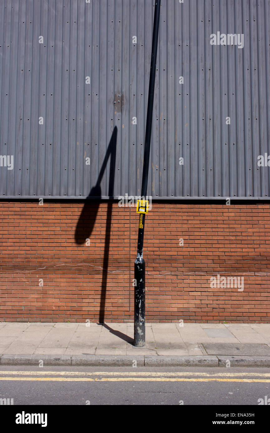 Leaning post and its own shadow on a brick wall in south London Stock ...