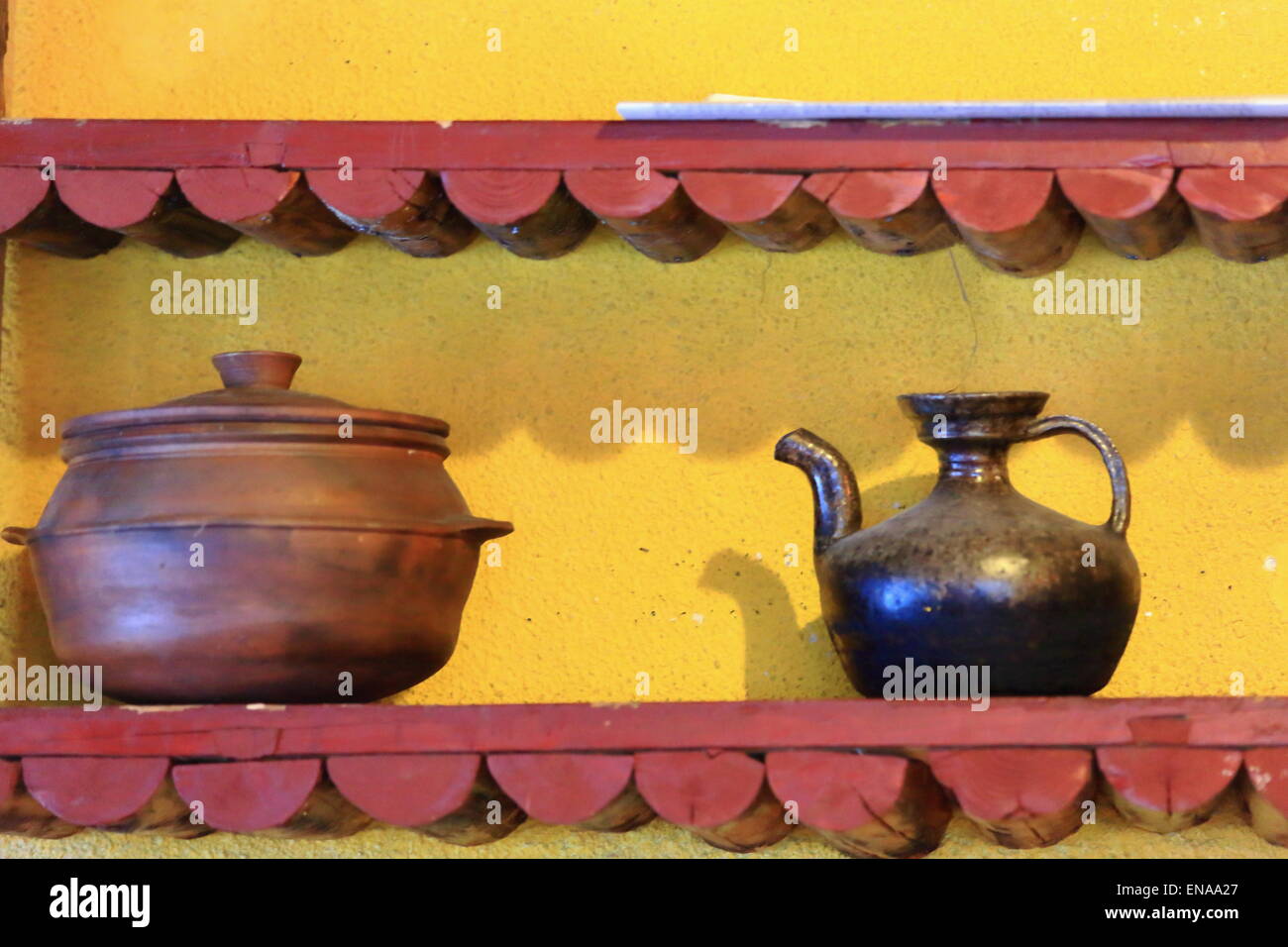 Old teapot and copper vessel set on red wooden shelf on the yellow wall ...