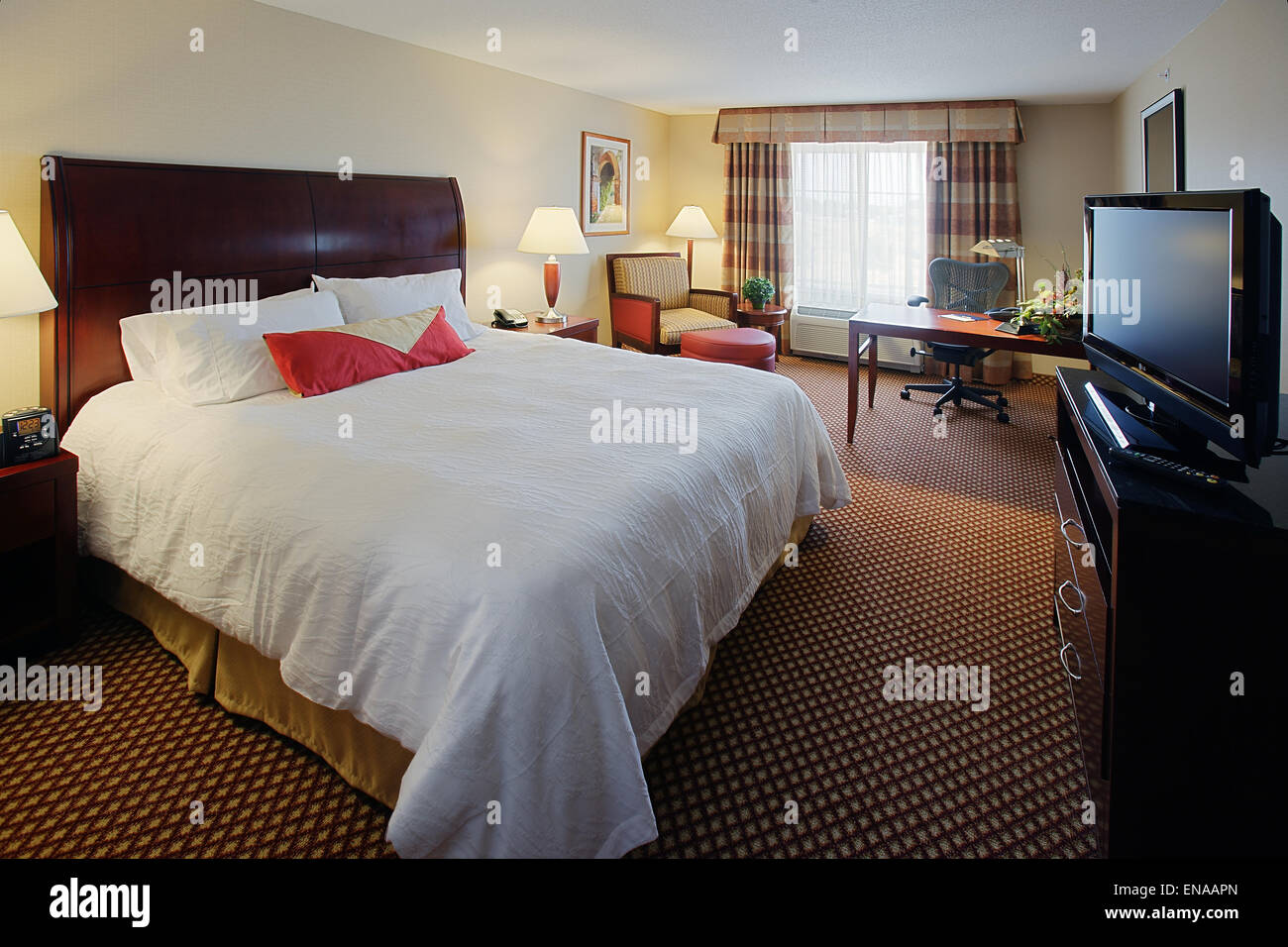An interior view of a midscale hotel suite, with a King sized bed and a ...