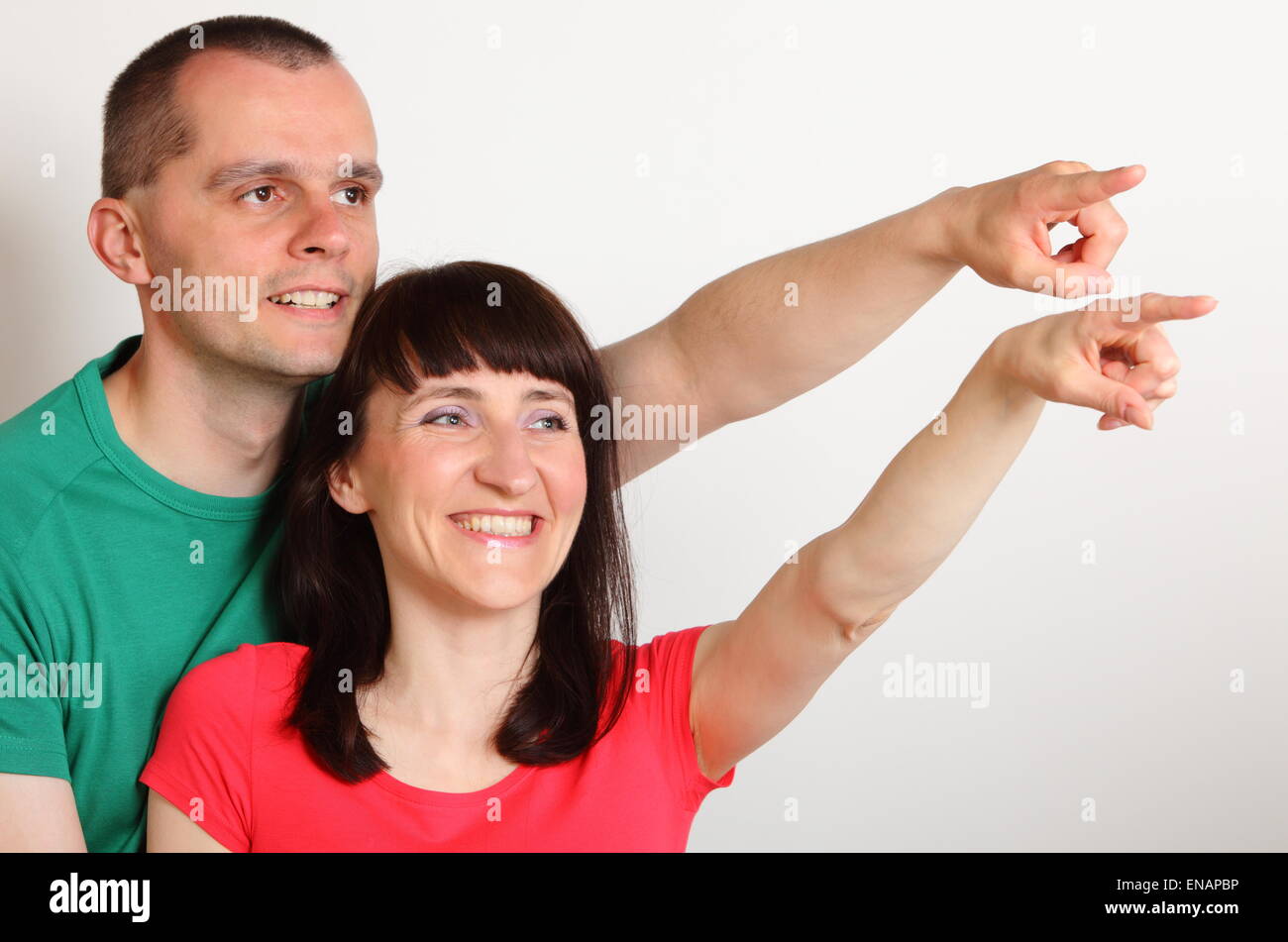 Smiling woman and man looking and pointing into distance, happy married ...