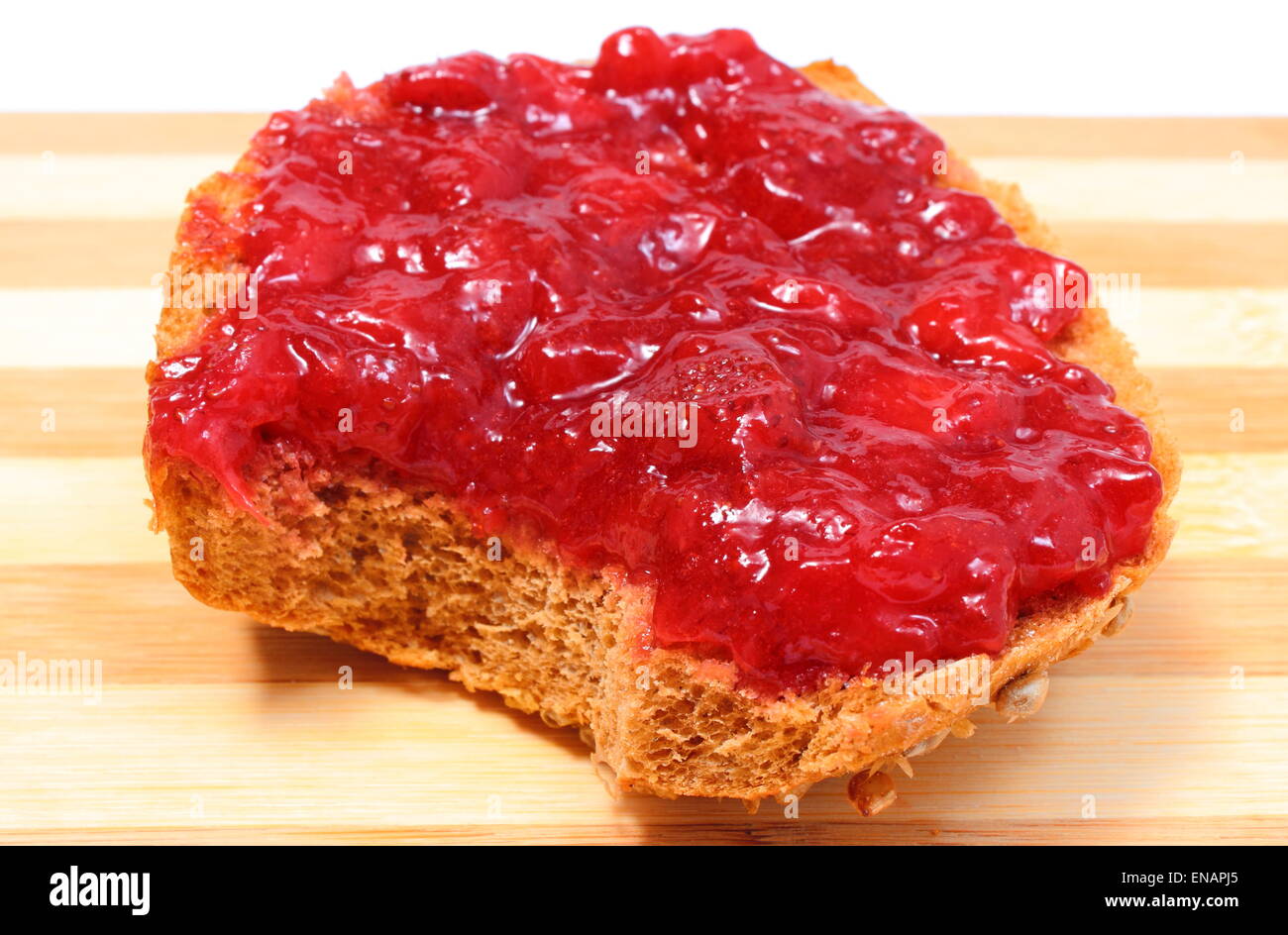 Portion of wheat bread with strawberry jam lying on wooden cutting ...