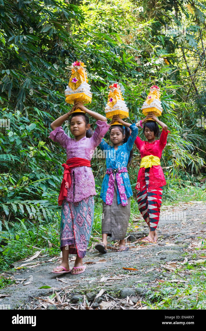 Three girls walking to the temple with offerings for a ceremony on the ...