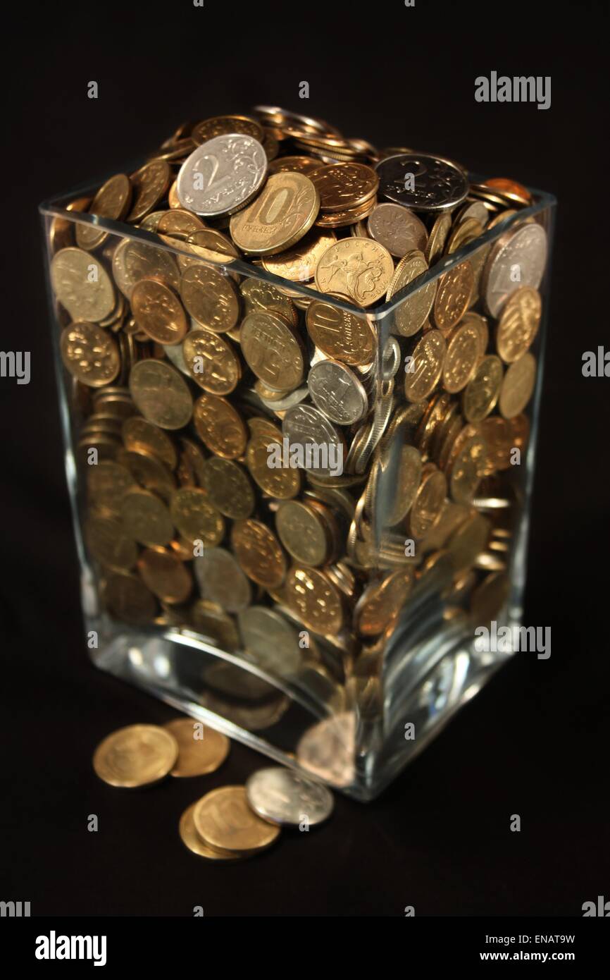 Coins in a glass jar on a black background Stock Photo - Alamy