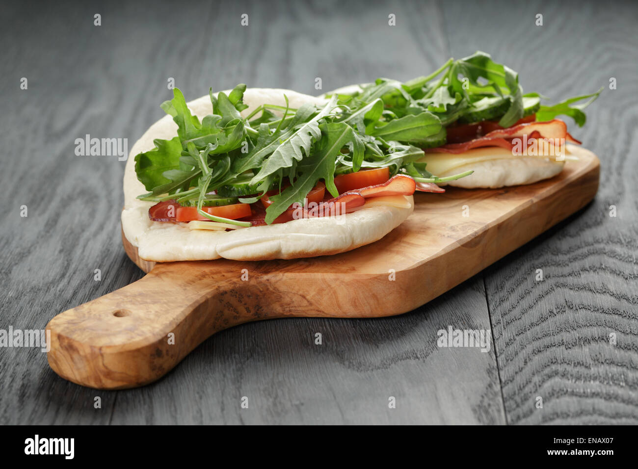 rustic sandwiches with ham arugula and tomatoes in pita bread, on wood ...