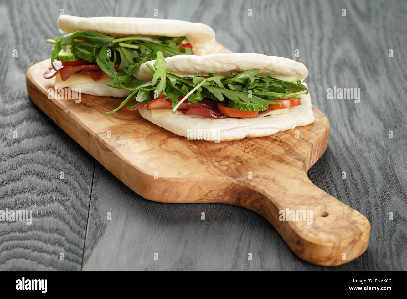 rustic sandwiches with ham arugula and tomatoes in pita bread, on wood ...
