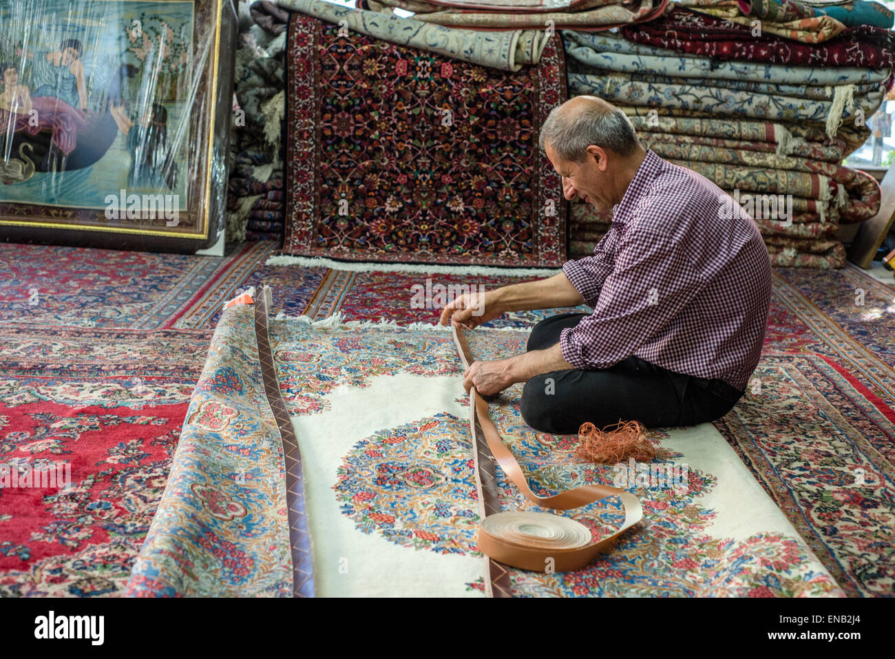 Worker sew underneath to Persian carpet in the carpet shop, Tehran ...
