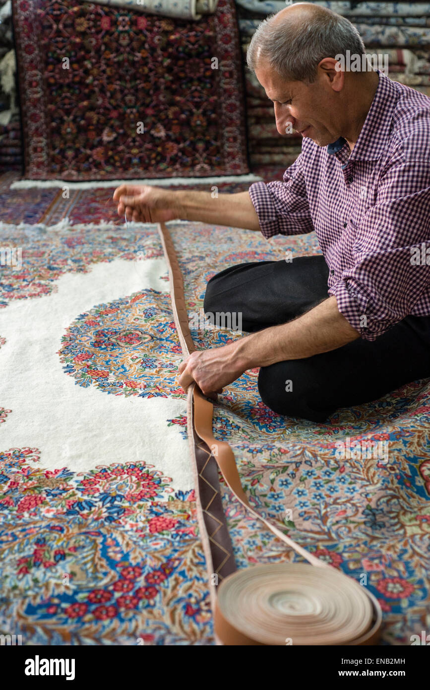 Worker sew underneath to Persian carpet in the carpet shop, Tehran ...
