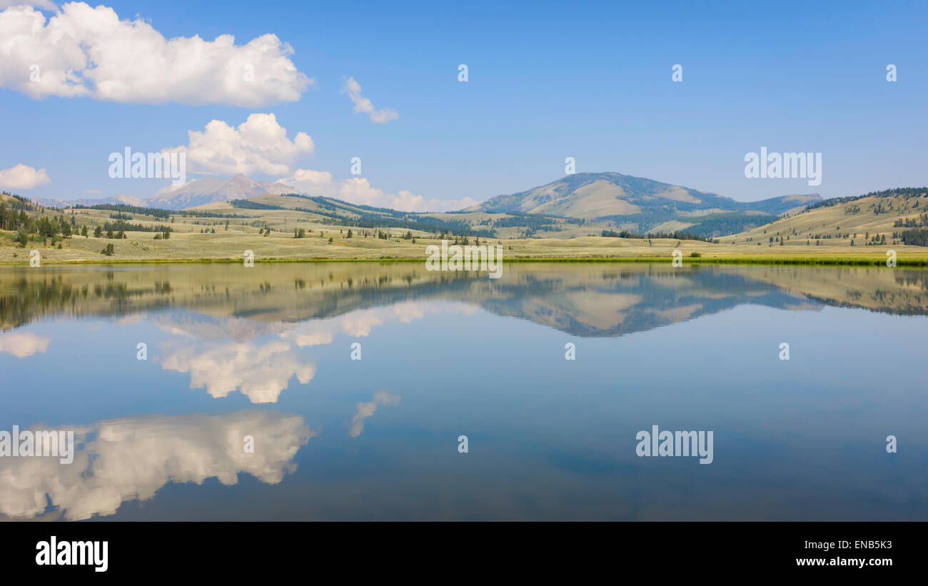 Reflections of hills, trees, snow peaked mountains on a bring sunny day ...