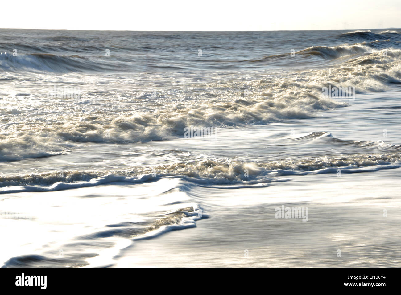 White surf bubbles up a sandy beach Stock Photo - Alamy