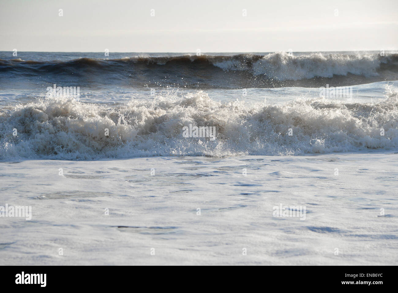 White surf bubbles up a sandy beach Stock Photo - Alamy