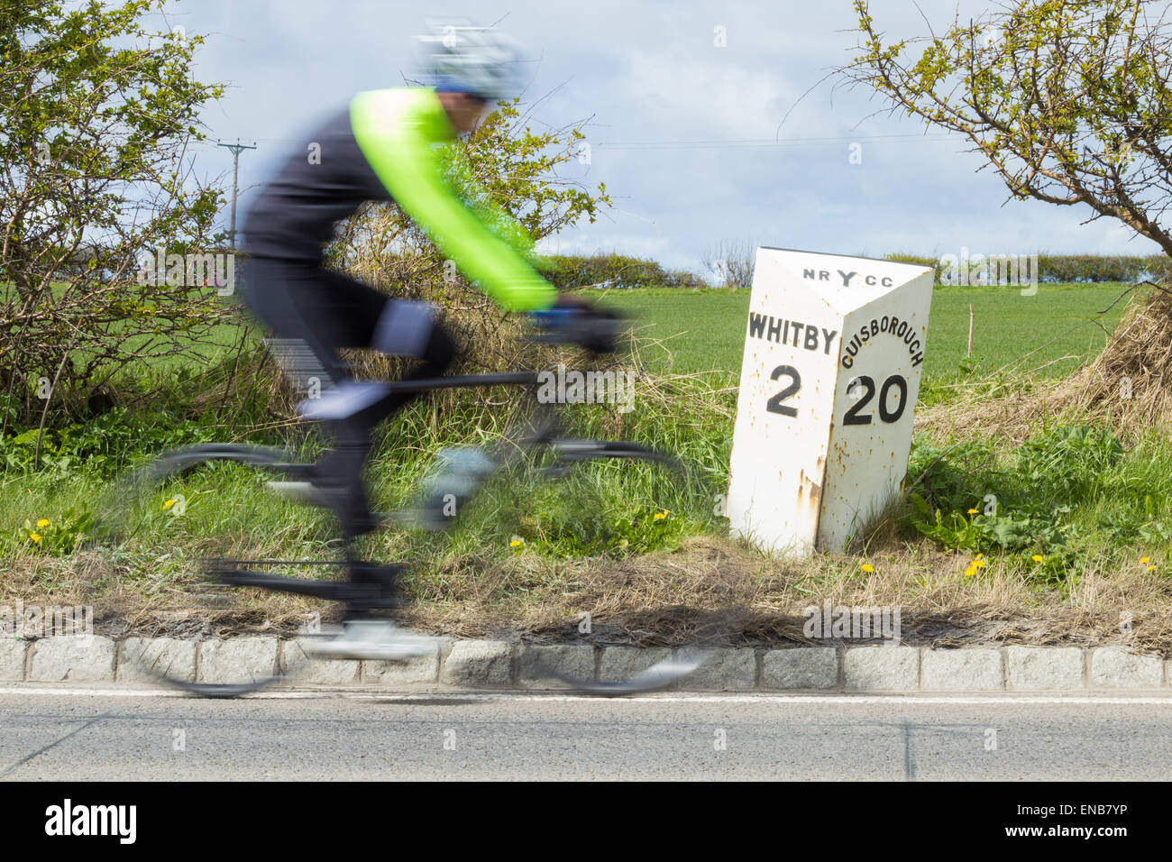 Cyclist passing stone road sign, milestone near Whitby, North Yorkshire ...