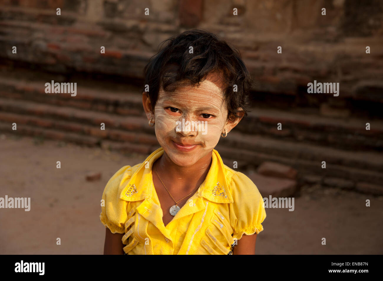 Portrait of a small Burmese girl wearing yellow top with sandalwood ...