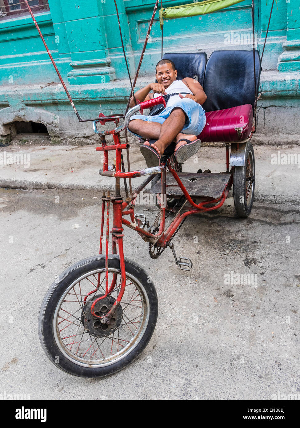 A Hispanic pedicab driver lies down on the seat of his pedicab and ...