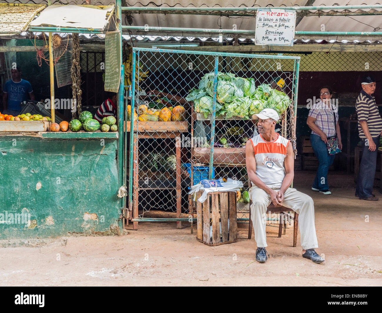 An Afro-Cuban man sits just outside a public market with vegetables on ...