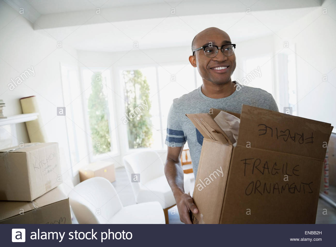 Smiling man carrying fragile moving box Stock Photo - Alamy