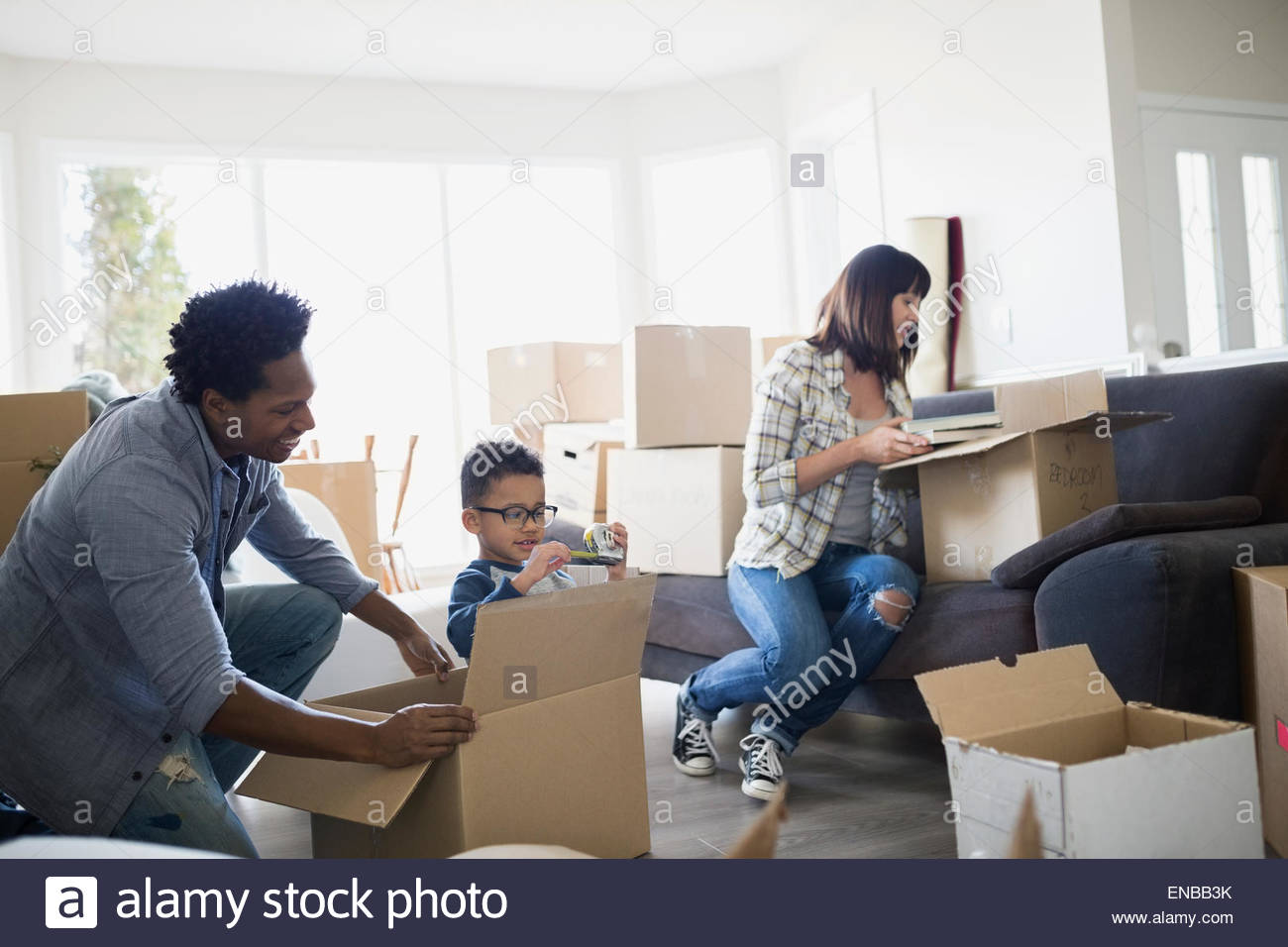 Family unpacking moving boxes in living room Stock Photo - Alamy