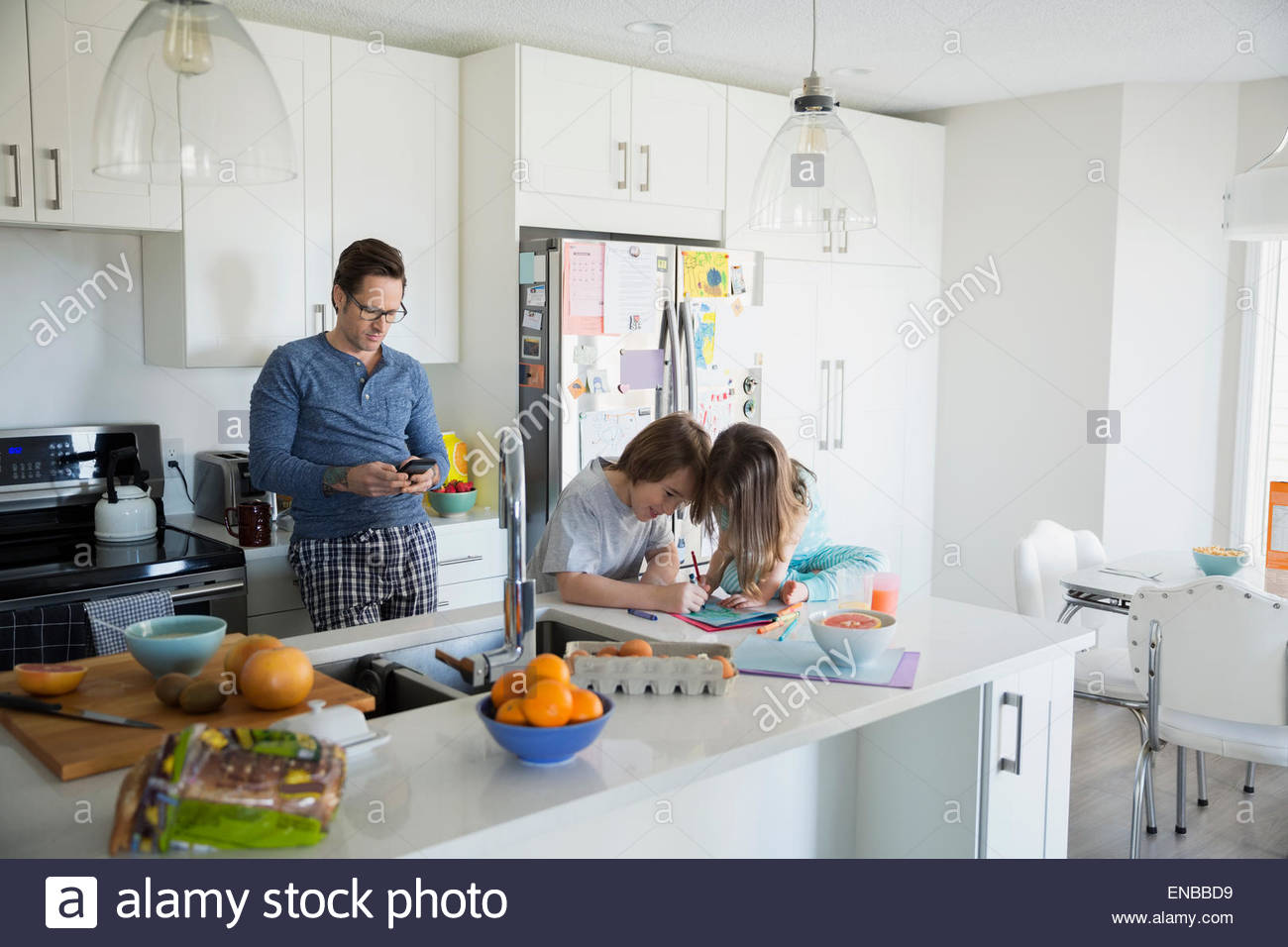 Father texting while children color in morning kitchen Stock Photo - Alamy