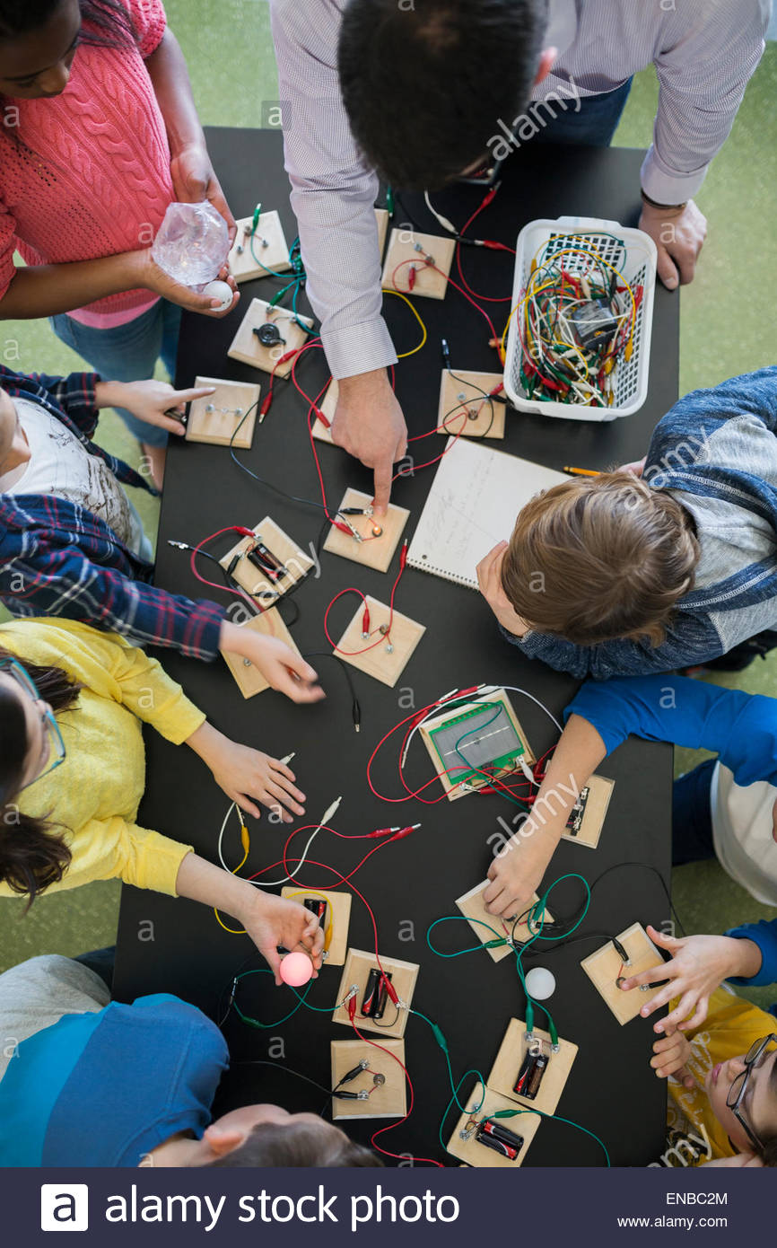 Students and teacher assembling circuit electronics at table Stock ...