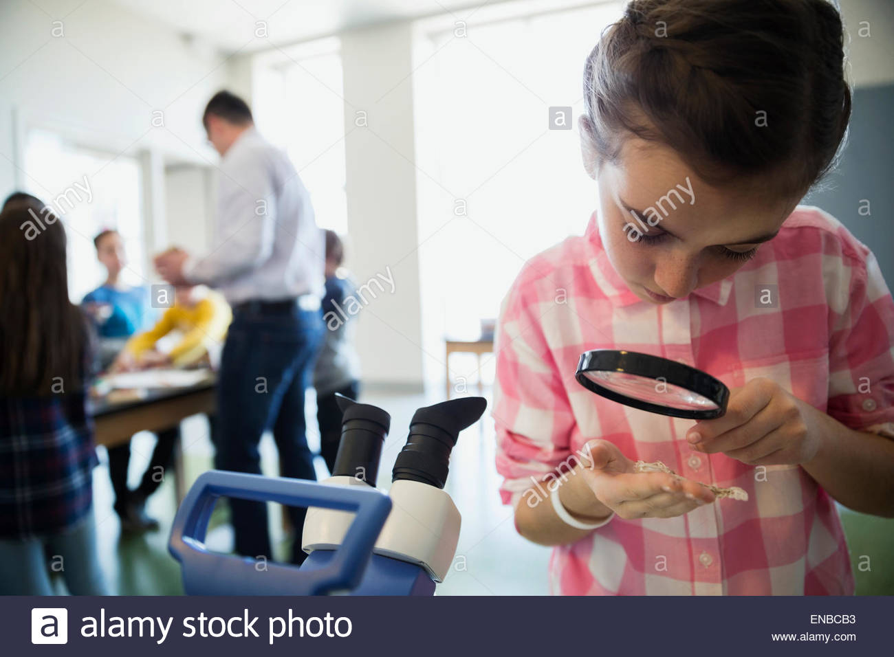 Curious schoolgirl with magnifying glass examining object Stock Photo ...