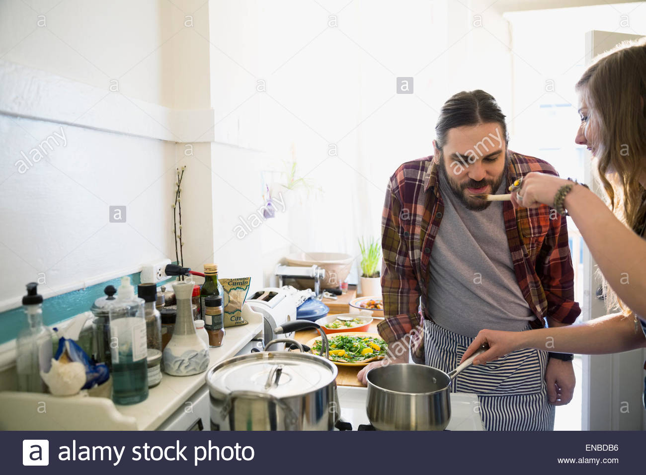 Couple cooking and tasting in kitchen Stock Photo - Alamy