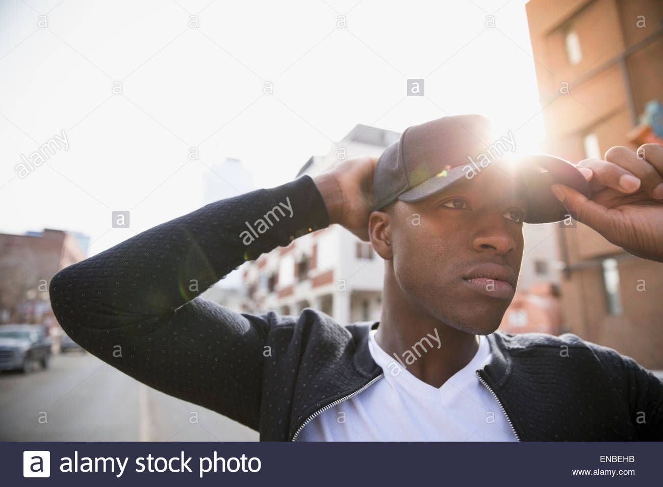 Serious man adjusting baseball cap urban street Stock Photo - Alamy