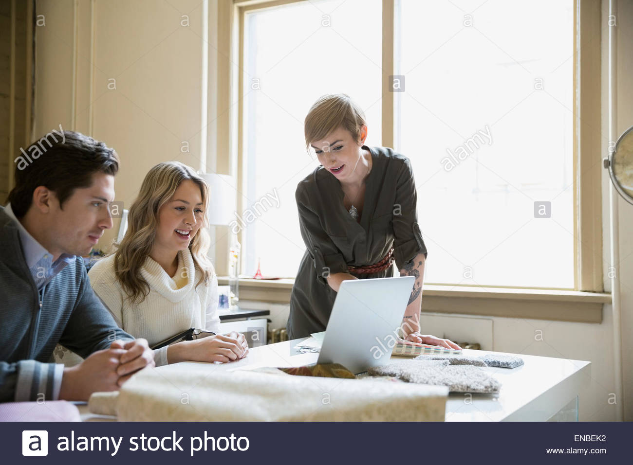 Interior designer presenting to couple at laptop in office Stock Photo ...