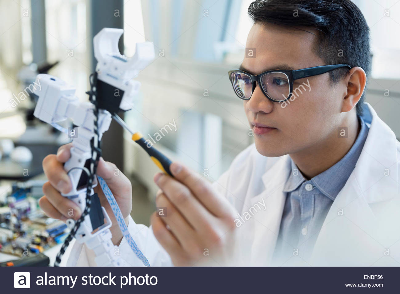 Focused engineer in lab coat assembling robotic arm Stock Photo - Alamy