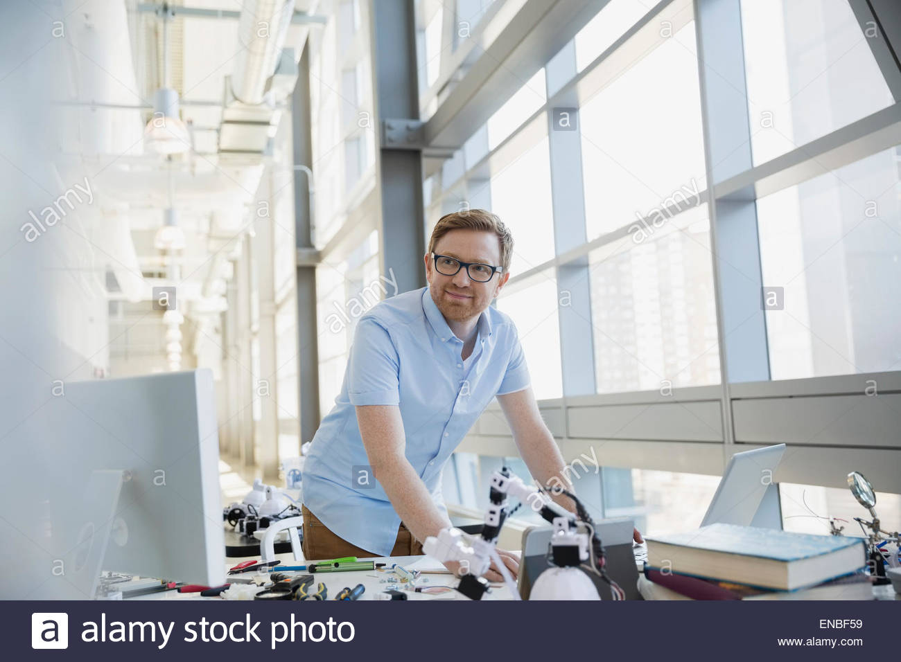 Smiling engineer working at desk with robotics Stock Photo - Alamy