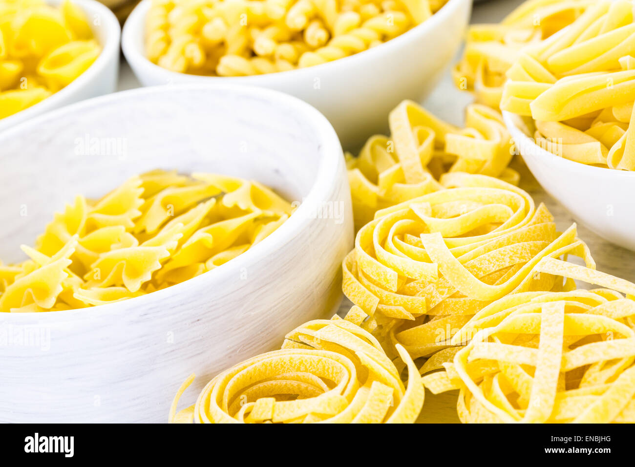 Variety of yellow dry pasta in small round bowls Stock Photo - Alamy