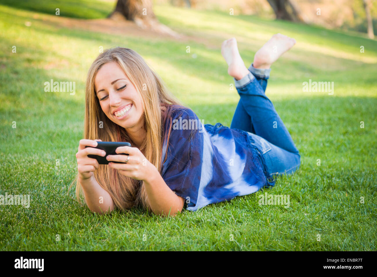 Smiling Young Woman Using Cell Phone Outdoors at the Park Stock Photo ...