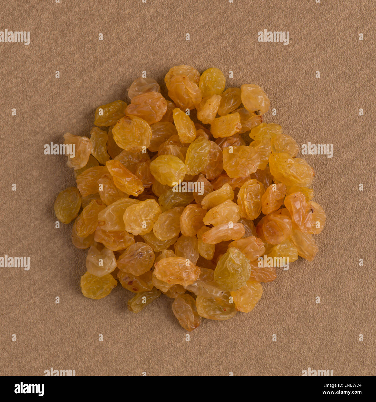Top view of circle of golden raisins against brown vinyl background ...