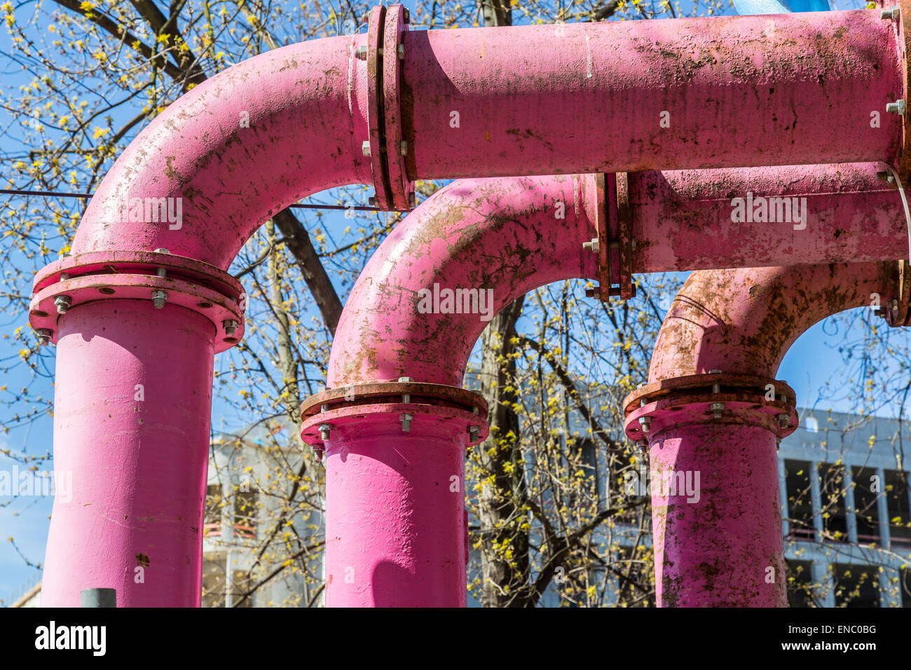 Large pipes, bent at right angles, at a subway construction site, pink ...