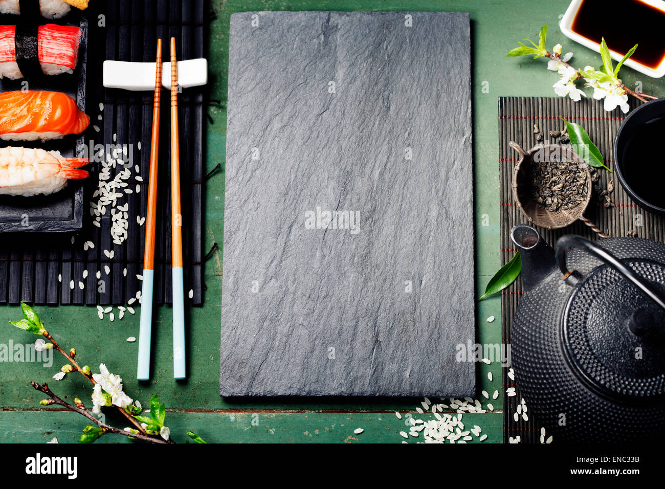Asian food background (black iron tea set and sushi on rustic table ...