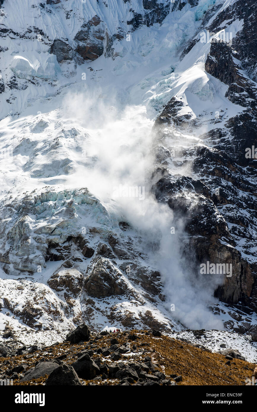 Group of people standing watching an avalanche on Salkantay, a mountain ...