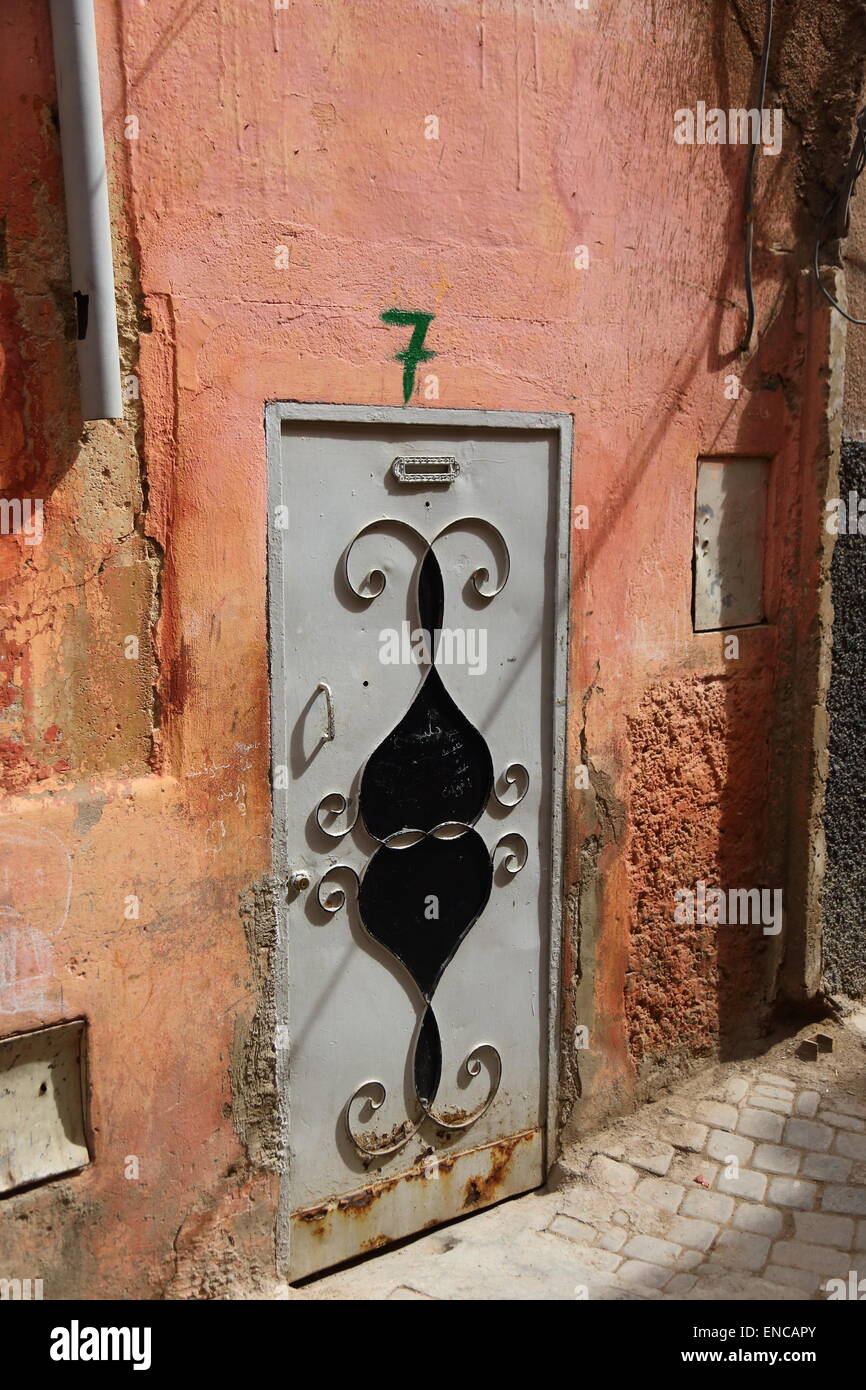 A grey door with the number 7 set in red walls in a back street in ...