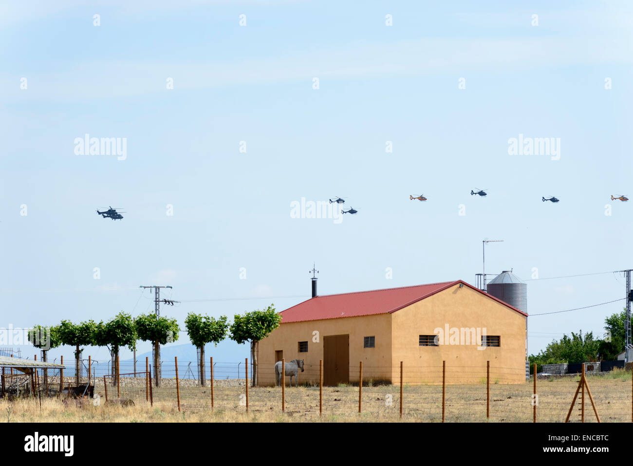 A few Eurocopter Super Puma helicopters flying in line over a farm ...