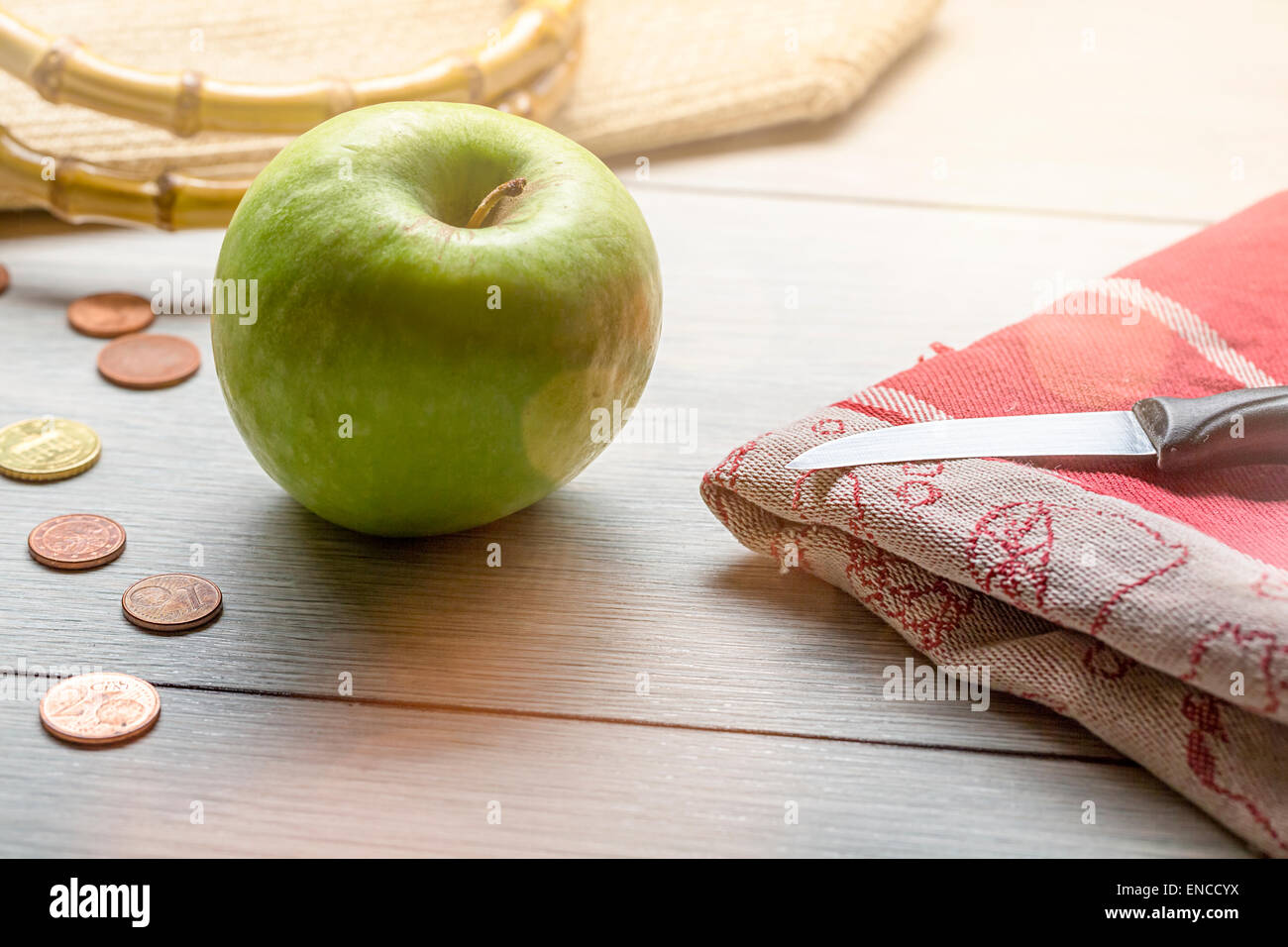 still life with green apple, some cent coins and a knife on a towel ...