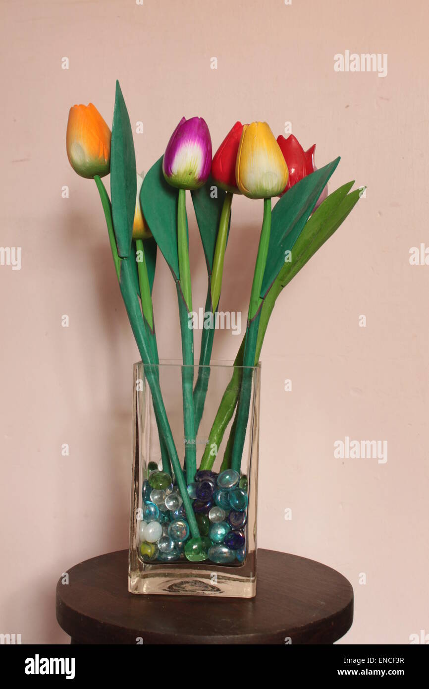 fake tulips in glass vase on small sidetable against pink background ...