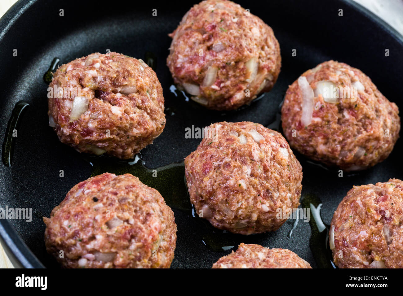 Frying large homemade Italian meatballs on a midium frying pan for ...