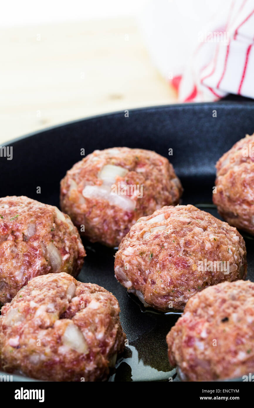 Frying large homemade Italian meatballs on a midium frying pan for ...