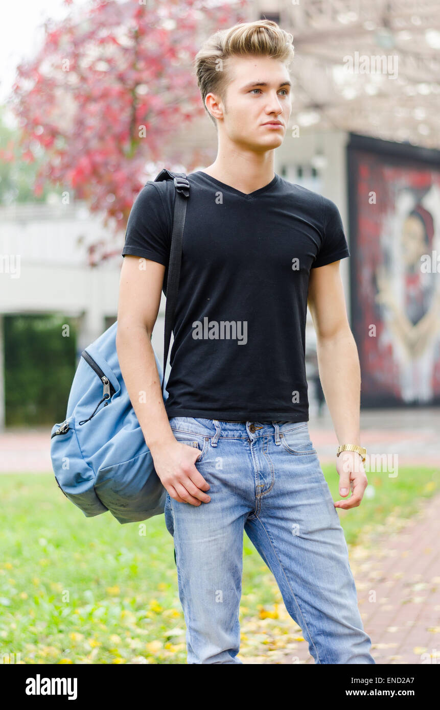Attractive young man with back pack standing outside Stock Photo - Alamy