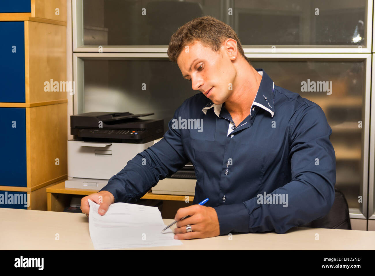 Young man doing paperwork at office desk, showing a document Stock ...