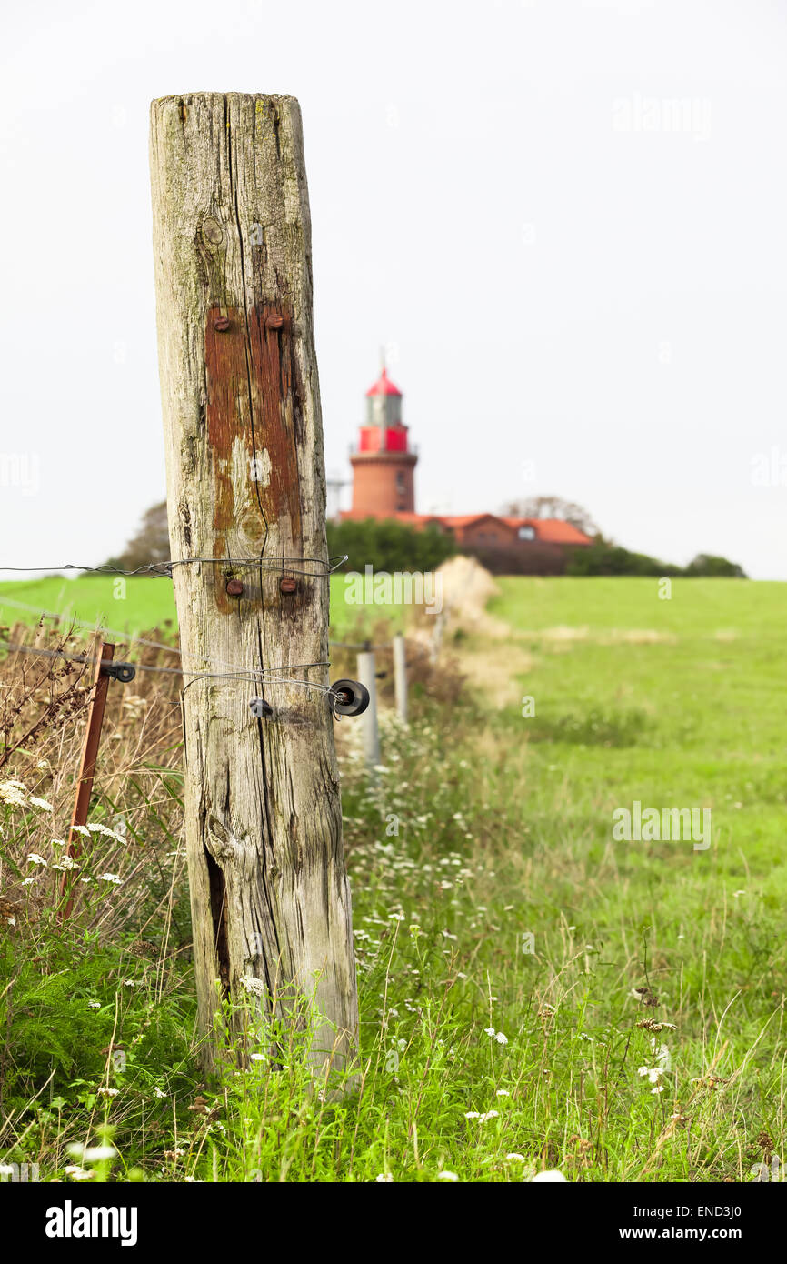 Wooden post on a meadow and a lighthouse in the distance Stock Photo ...