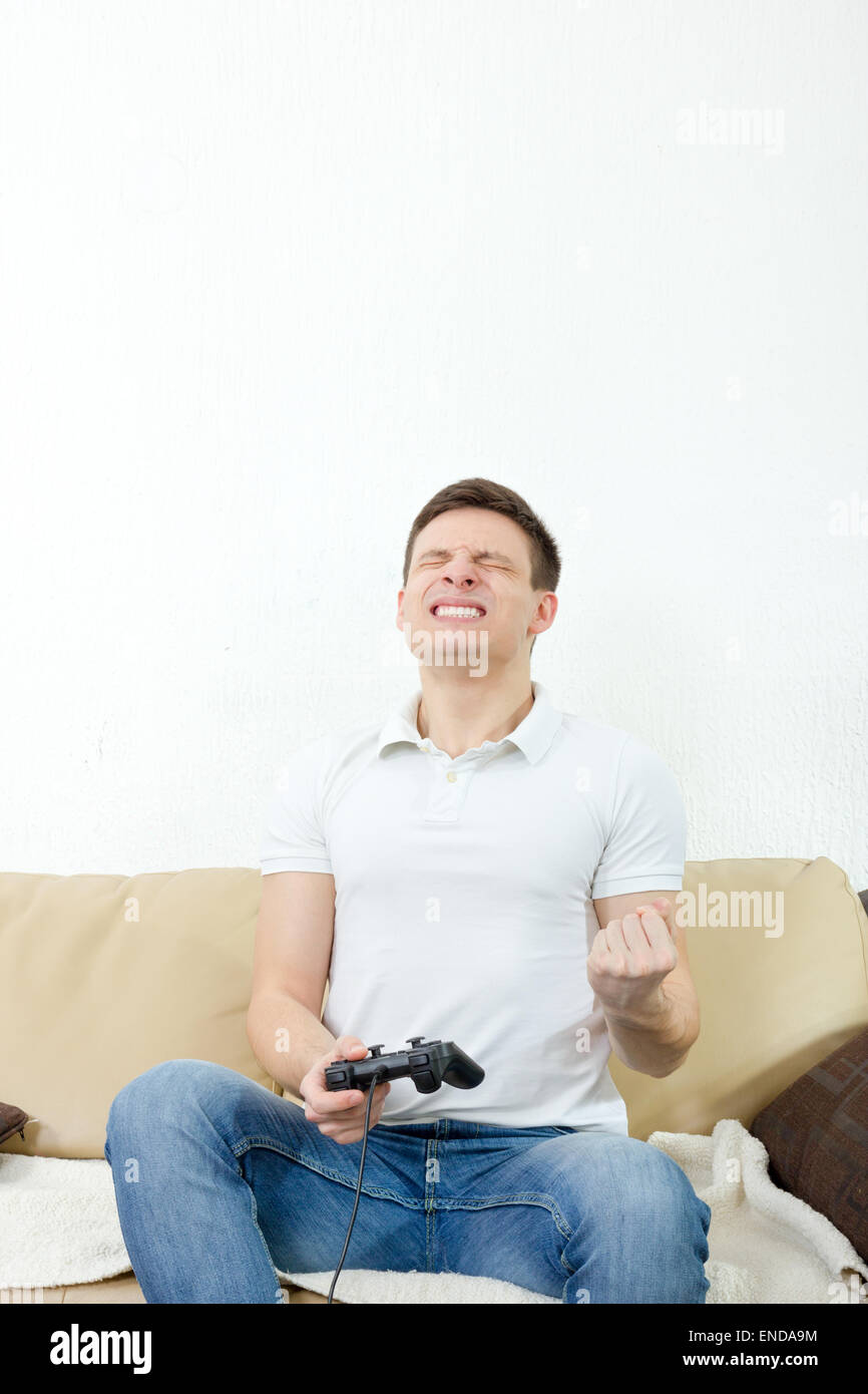 Emotional young man playing video games with joypad or joystick to ...