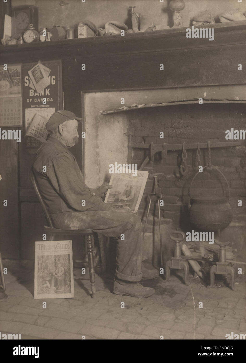 A photograph from around 1900 showing a man reading by a cozy fireplace ...