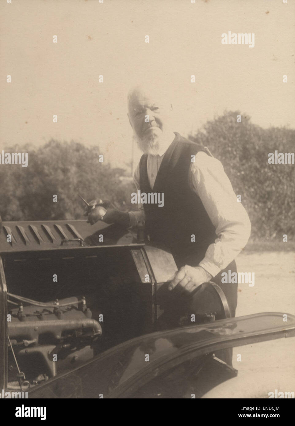 This historical photograph shows an individual oiling a motor vehicle ...