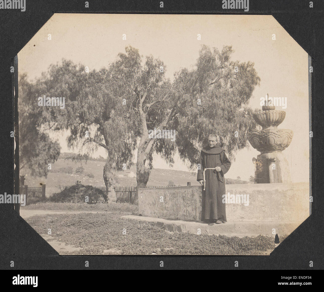 This historical photograph shows a monk at the Santa Barbara Mission ...