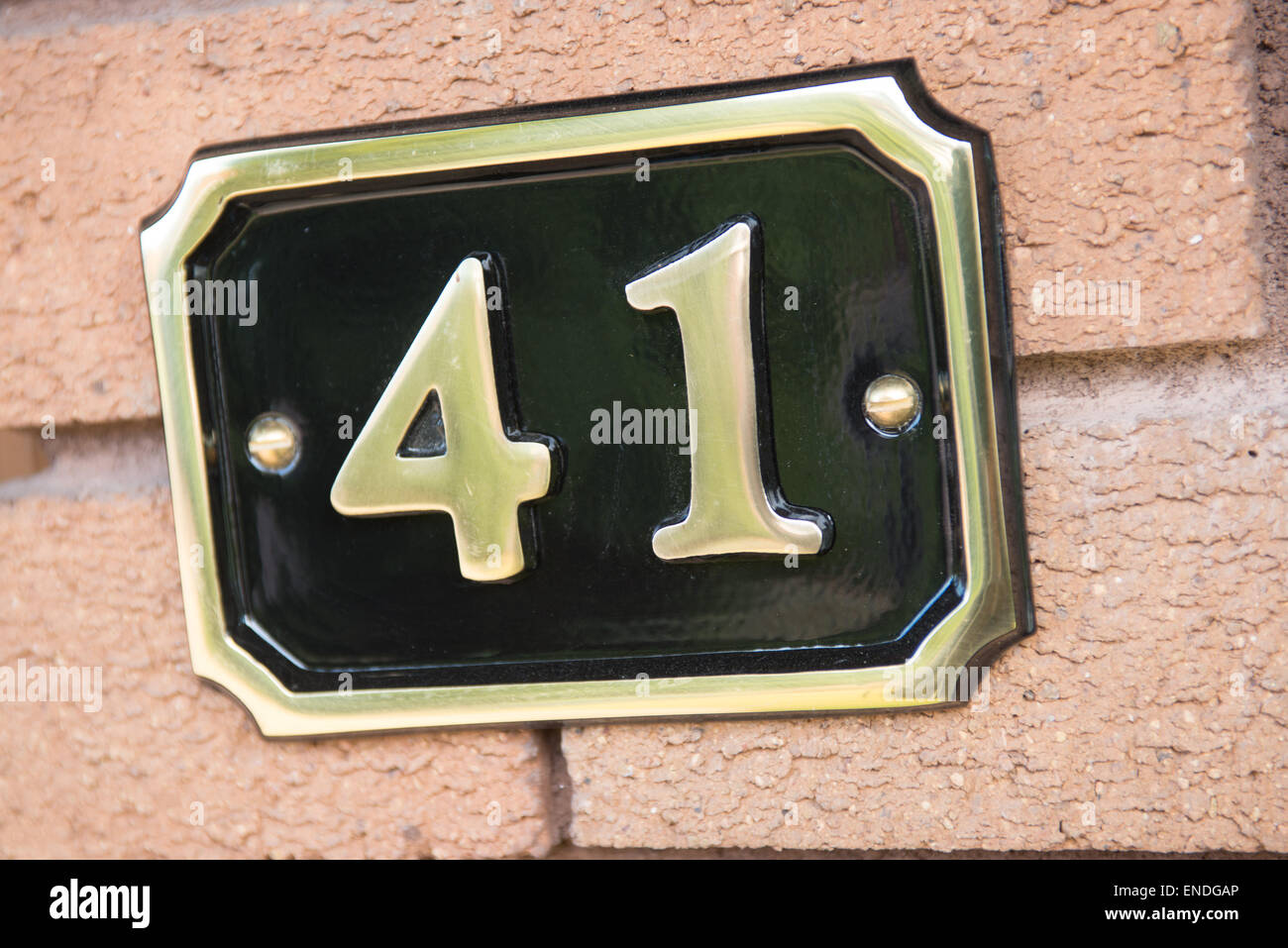 The brass plaque displaying the number 41 on a brick wall of a home ...