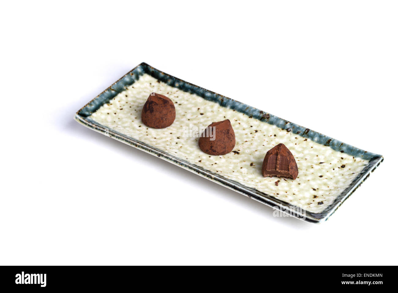 Three chocolate truffles on a ceramic plate with a pure white ...