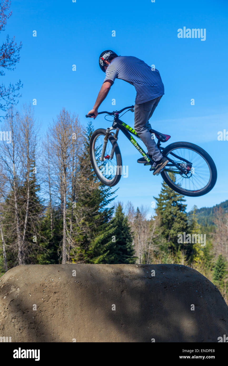 Action shot of a young man jumping over an obstacle on a bike track in ...